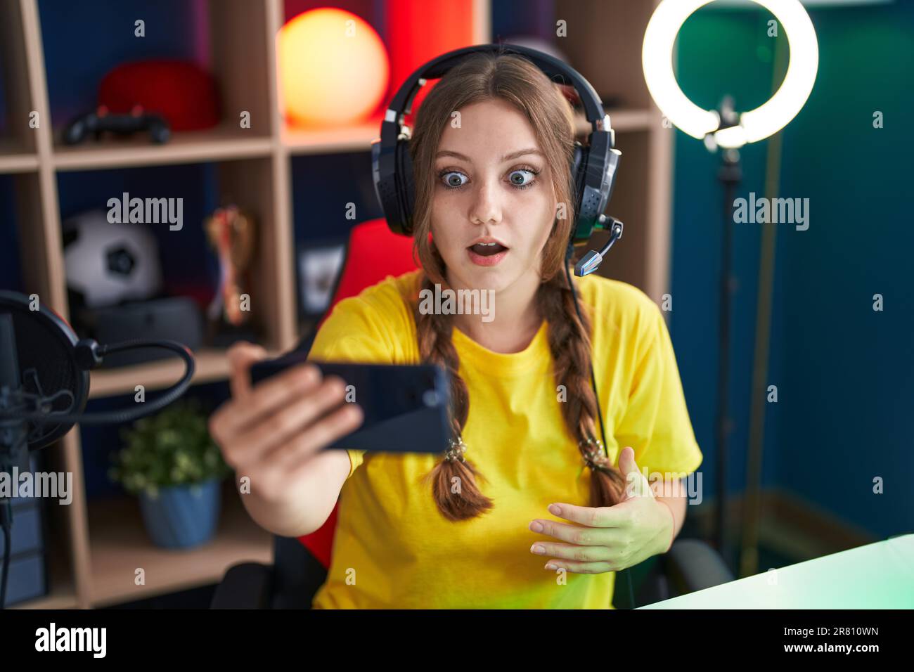 Young caucasian woman playing video games with smartphone scared and ...