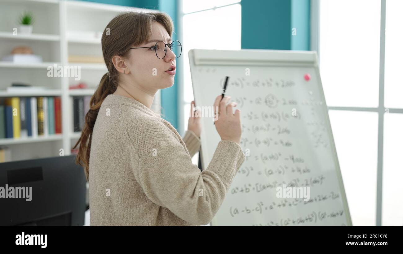 Young blonde woman teacher explaining maths lesson at library ...