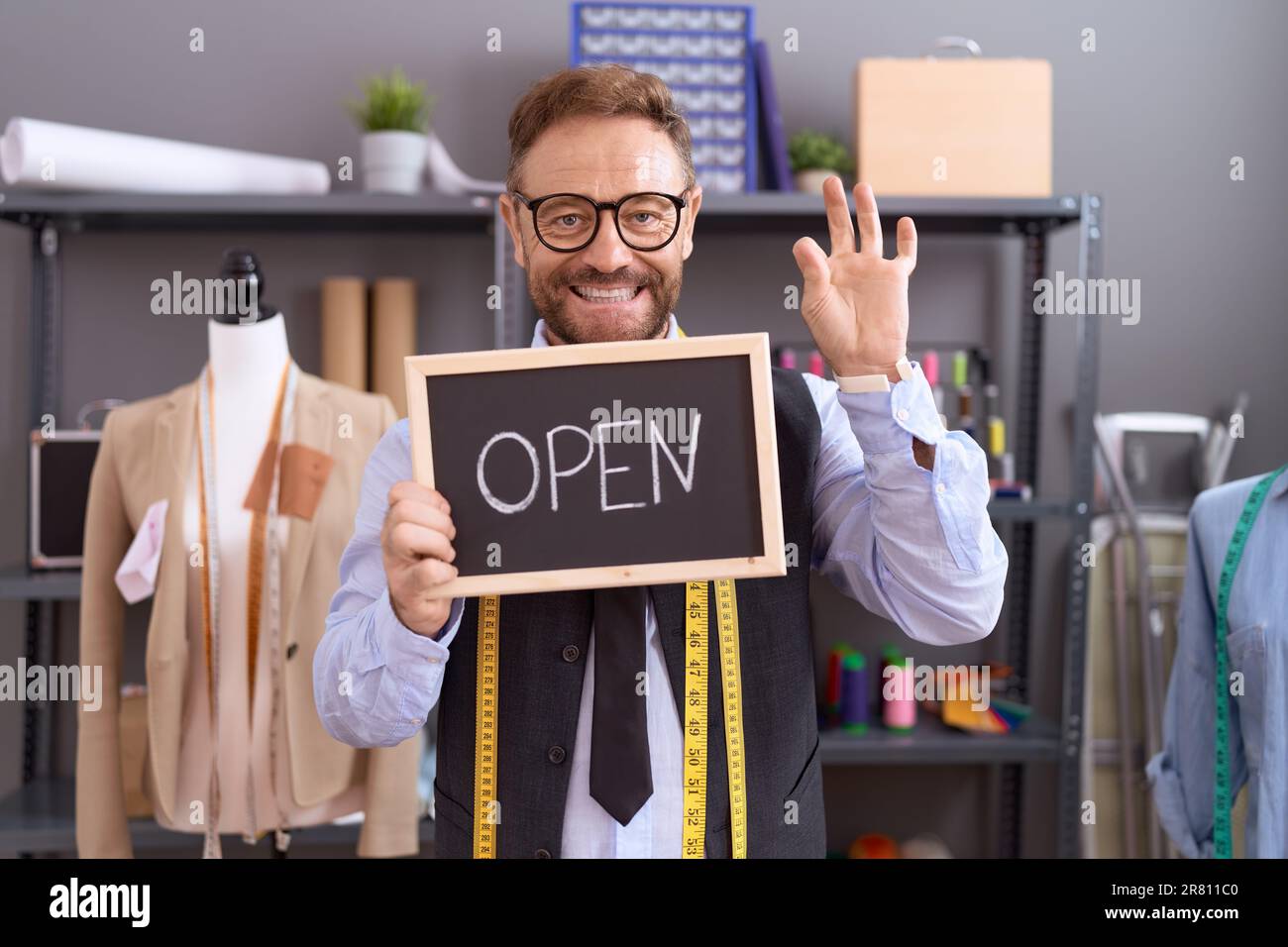 Middle age man with beard dressmaker designer holding open sign doing ...