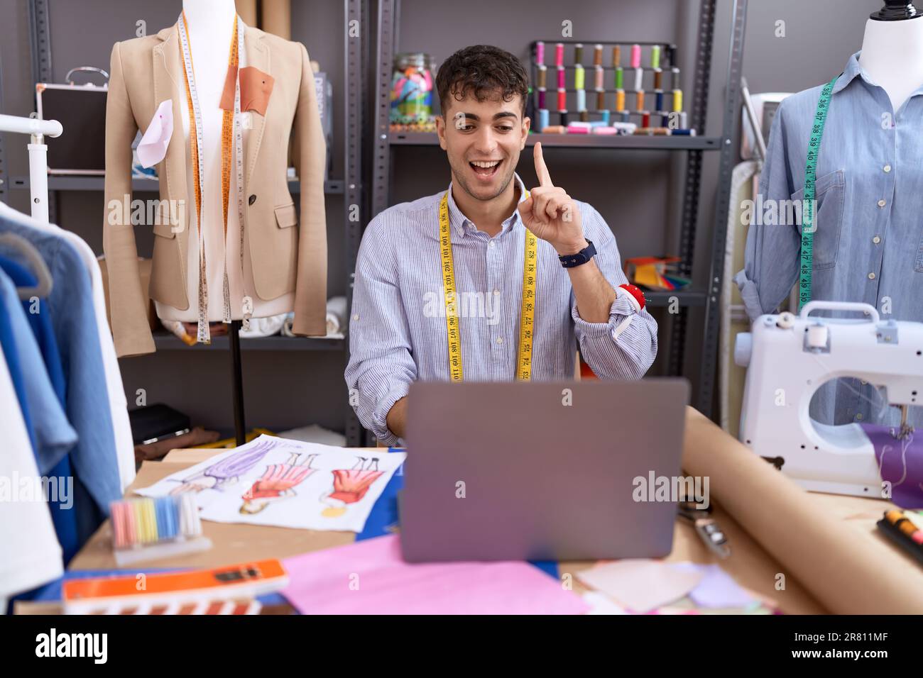Young hispanic man dressmaker designer using laptop smiling with an ...
