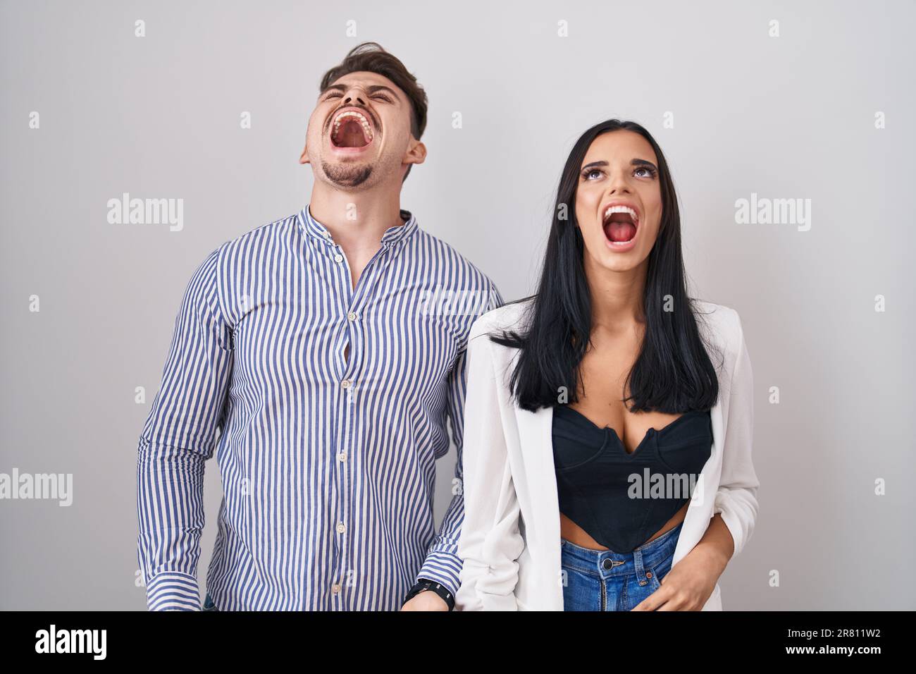 Young hispanic couple standing over white background angry and mad ...