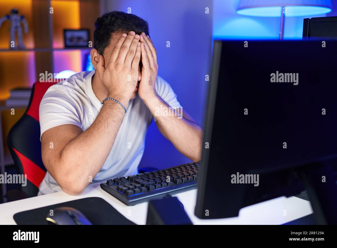 Young hispanic man streamer stressed using computer at gaming room ...