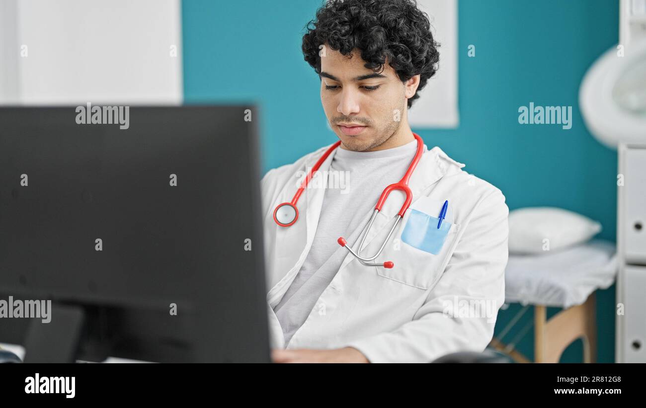 Young latin man doctor using computer working at clinic Stock Photo - Alamy