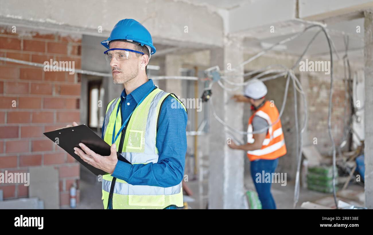 Two men builders writing document working at construction site Stock ...