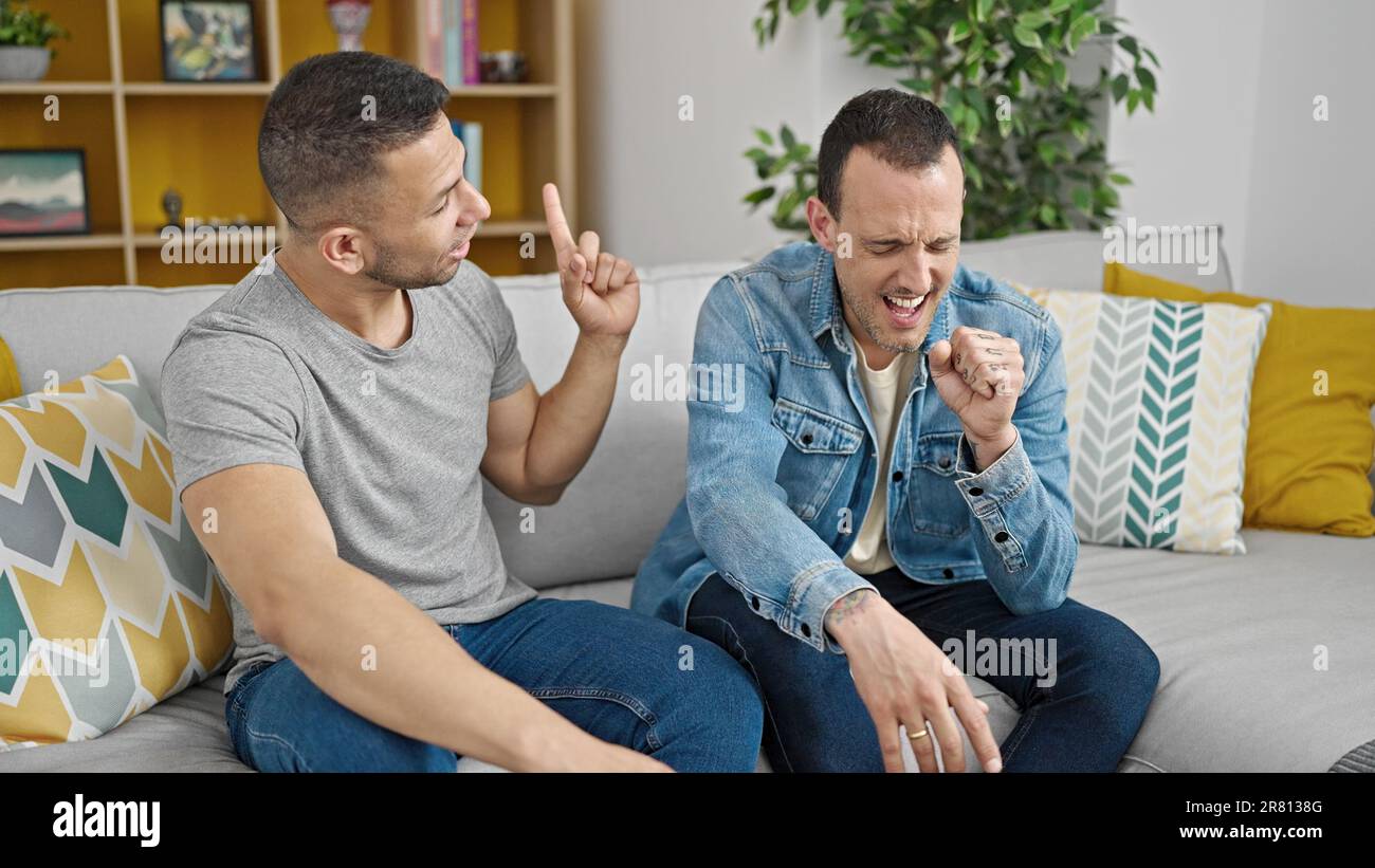 Two men couple sitting on sofa singing song at home Stock Photo - Alamy