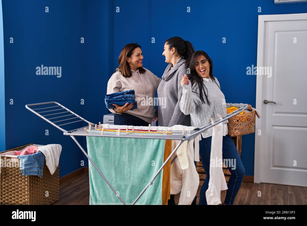 Three woman hanging clothes on clothesline and dancing at laundry room ...
