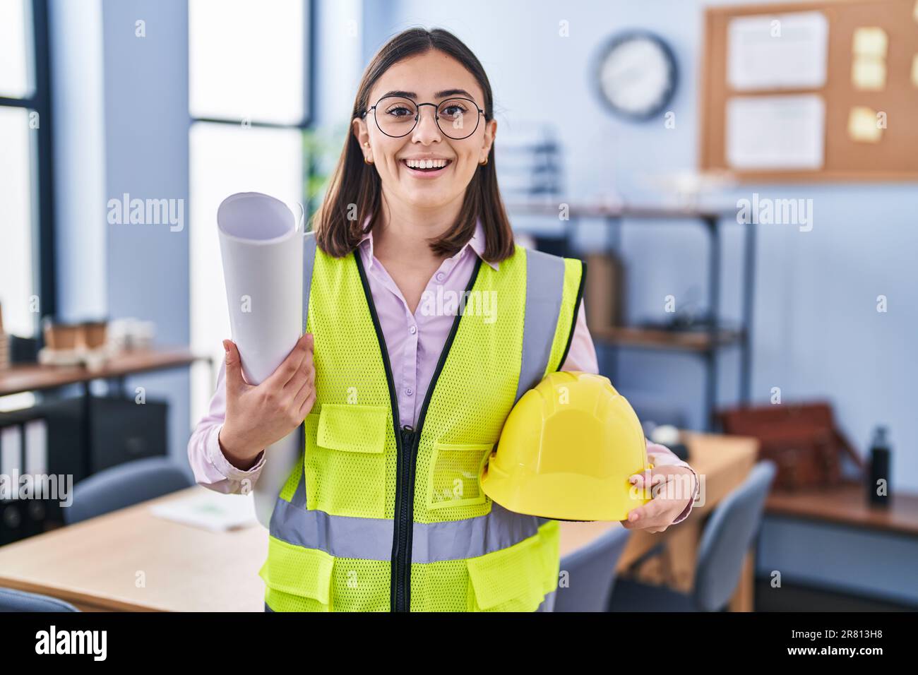 Hispanic girl architect holding build project blueprints smiling and ...