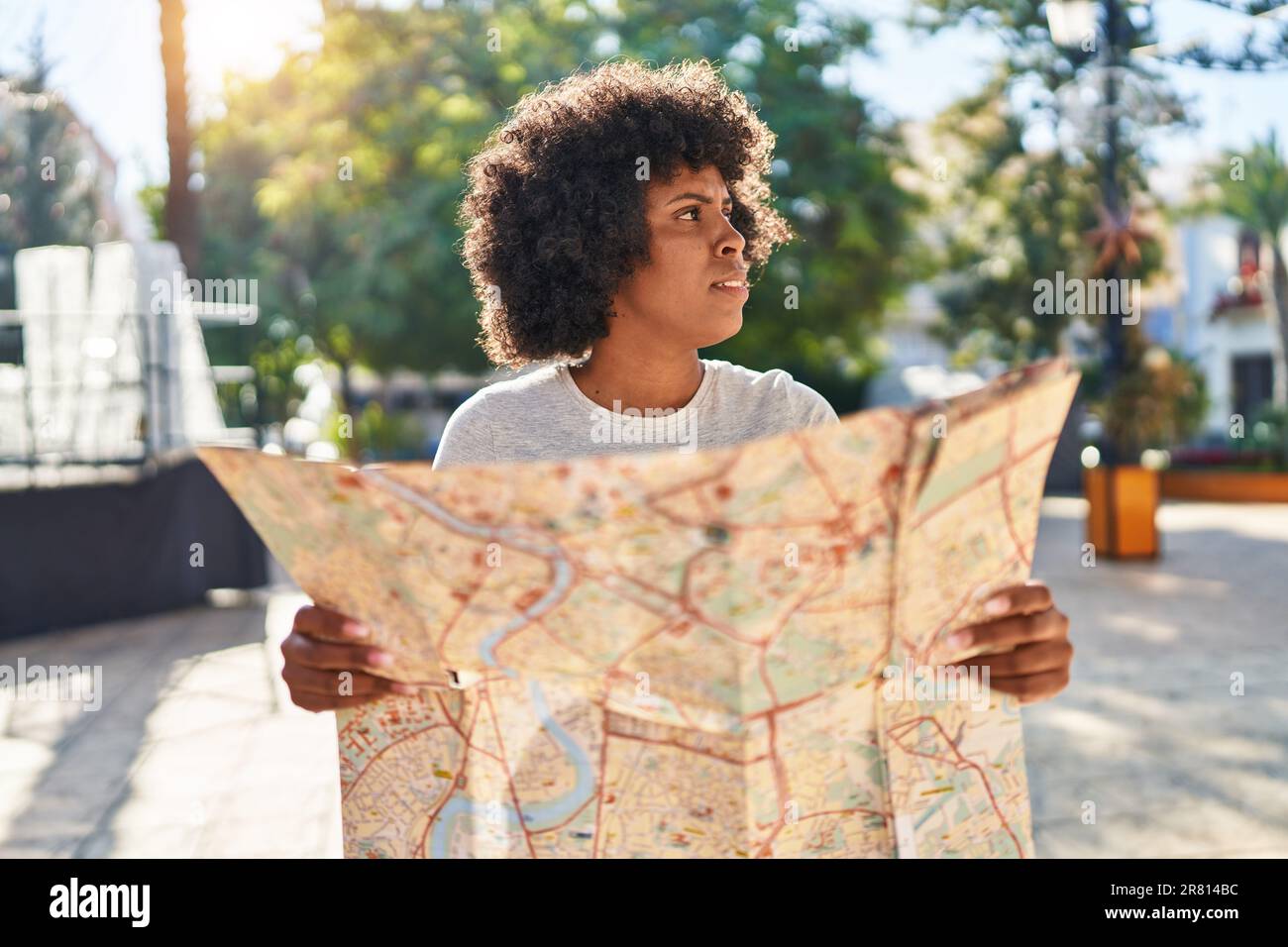 African american woman holding city map at park Stock Photo - Alamy