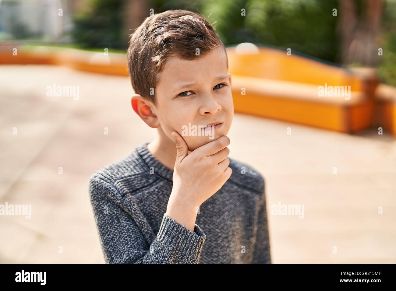 Blond child standing with doubt expression at park Stock Photo - Alamy