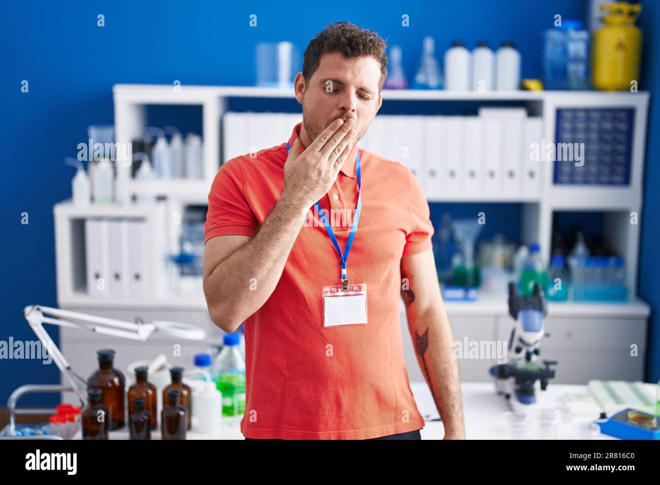 Young hispanic man working at scientist laboratory bored yawning tired ...