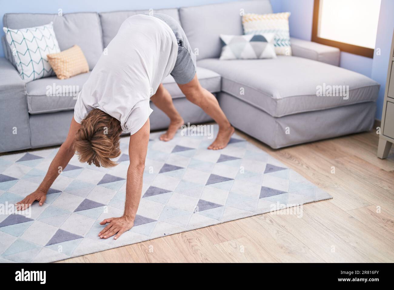 Young blond man stretching back at home Stock Photo - Alamy