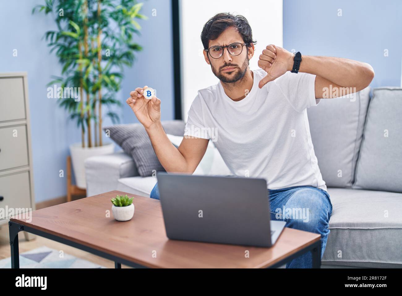 Handsome latin man holding virtual currency bitcoin using laptop with ...