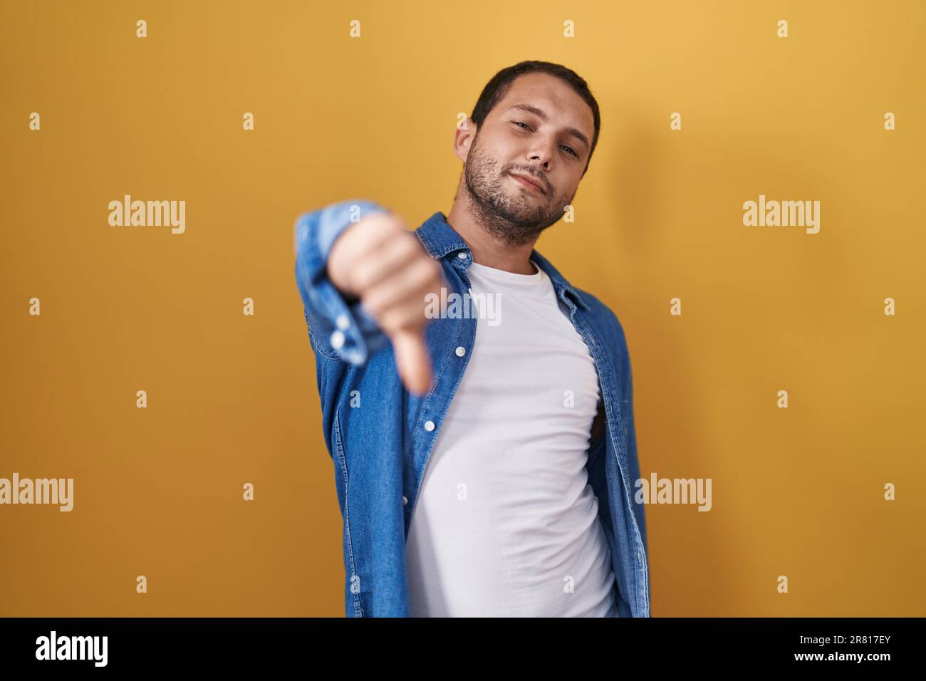 Hispanic man standing over yellow background looking unhappy and angry ...