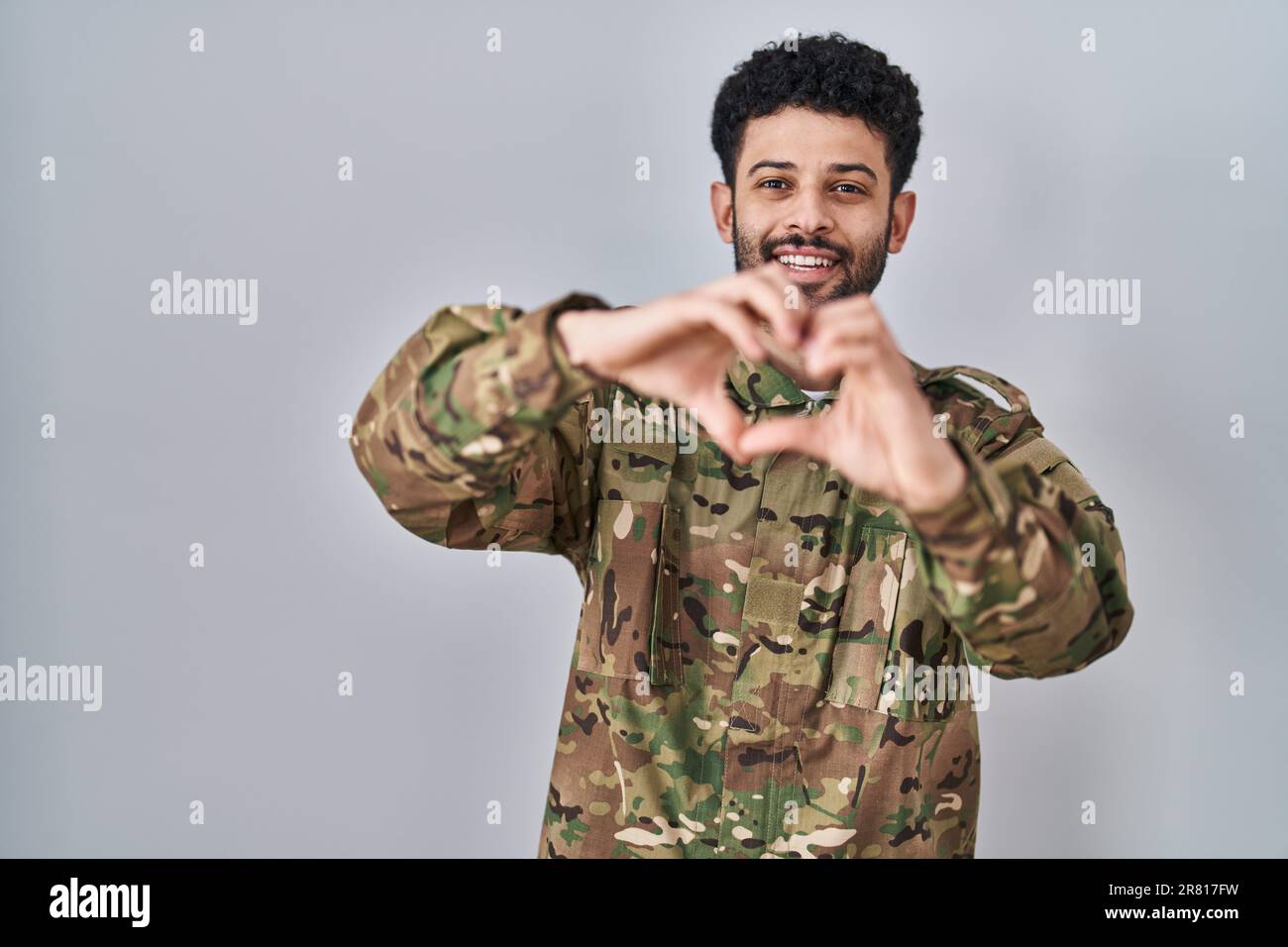 Arab man wearing camouflage army uniform smiling in love doing heart ...