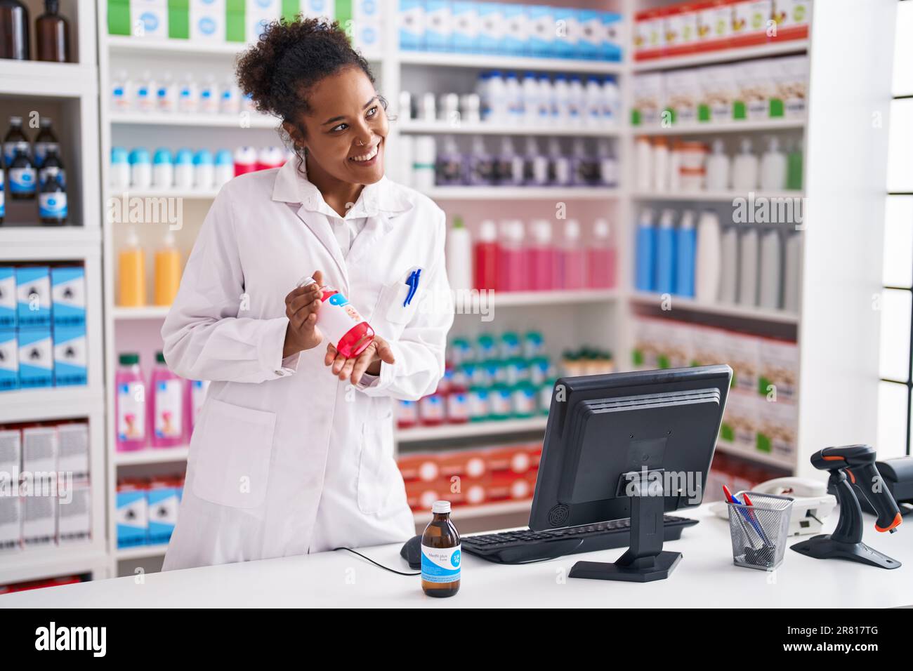 African american woman pharmacist using computer holding medication ...