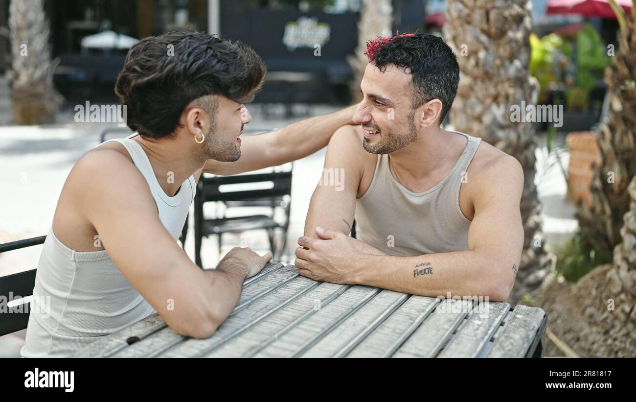 Two men couple sitting on table speaking at coffee shop terrace Stock Photo - Alamy