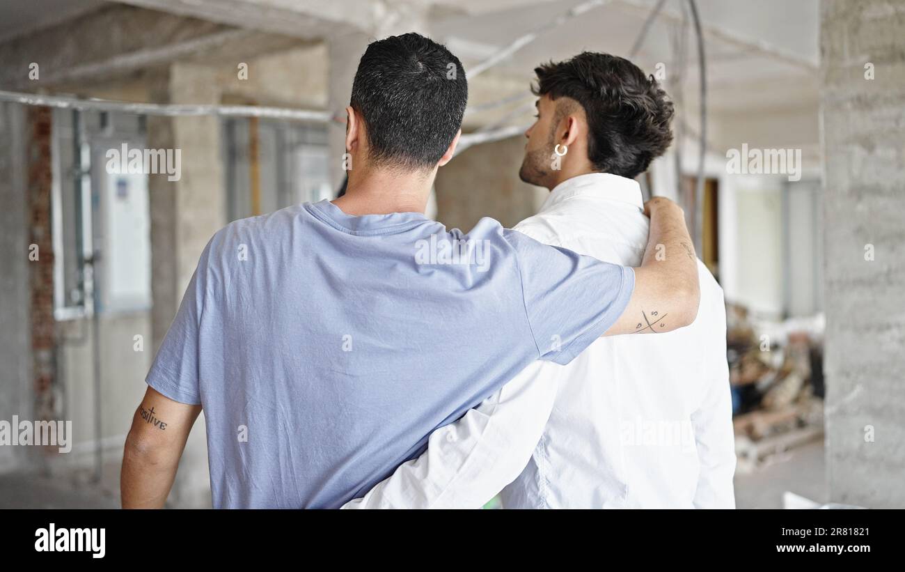 Two men couple hugging each other looking around at construction site ...