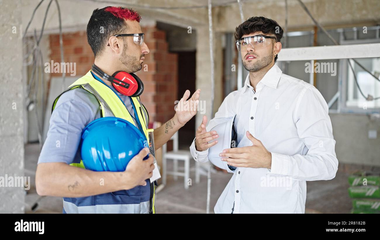 Two men builder and architect standing together speaking at ...