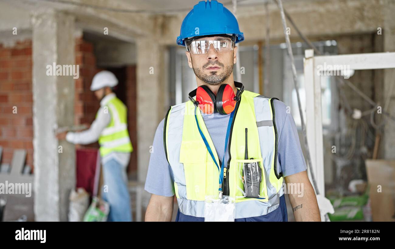 Two men builders standing with relaxed expressiona at construction site ...