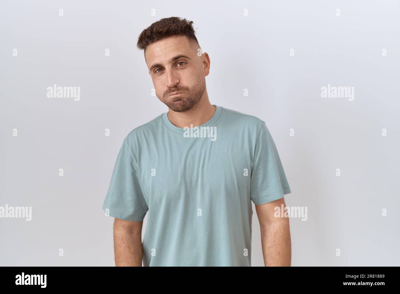Hispanic man with beard standing over white background puffing cheeks ...
