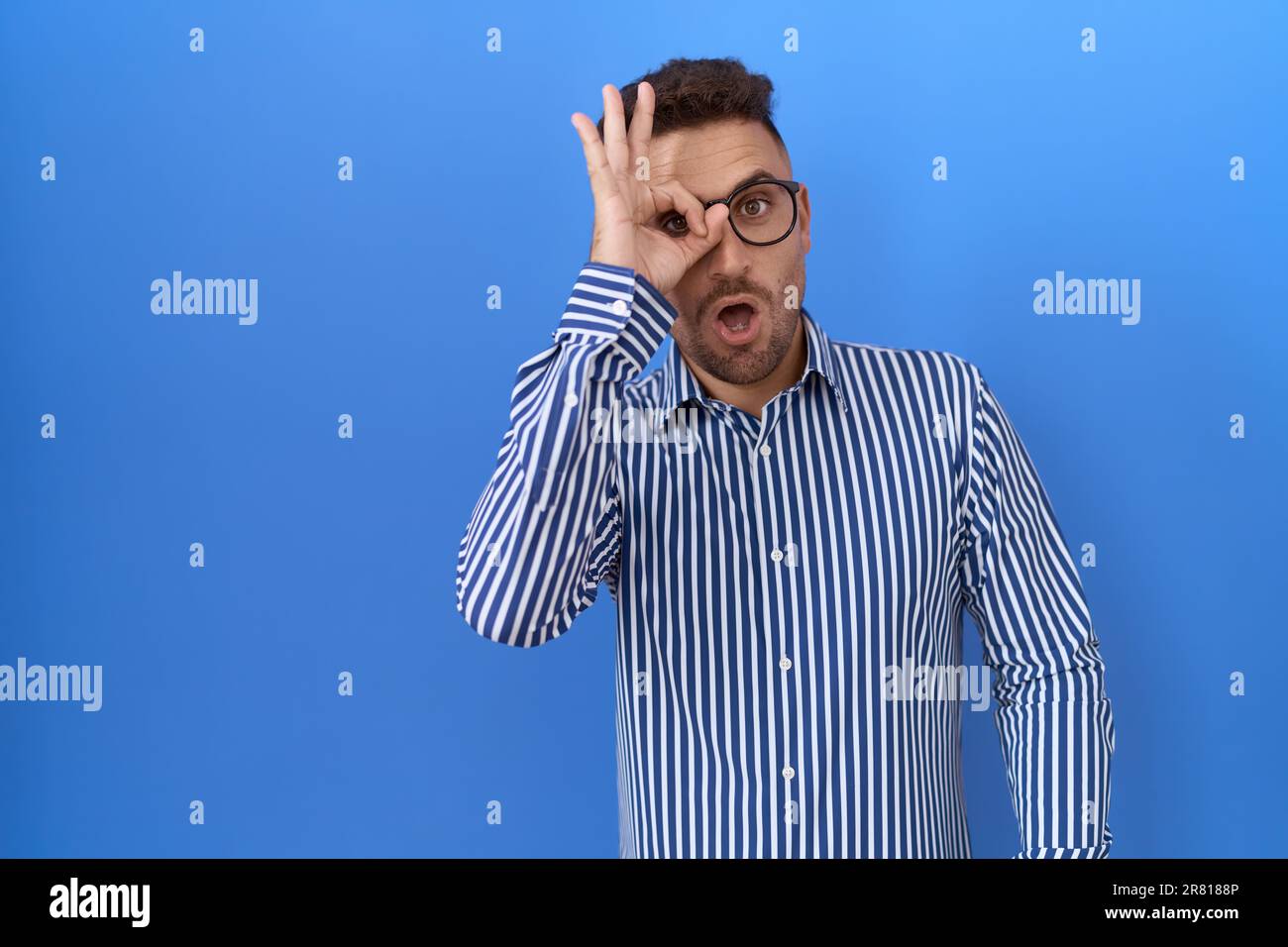 Hispanic man with beard wearing glasses doing ok gesture shocked with ...