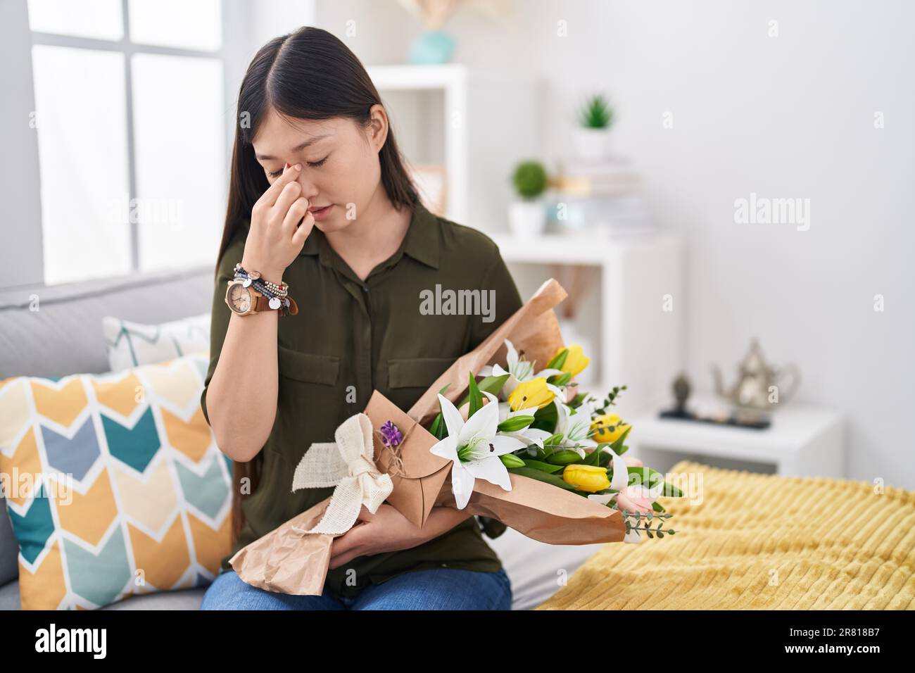 Chinese young woman holding bouquet of white flowers tired rubbing nose ...