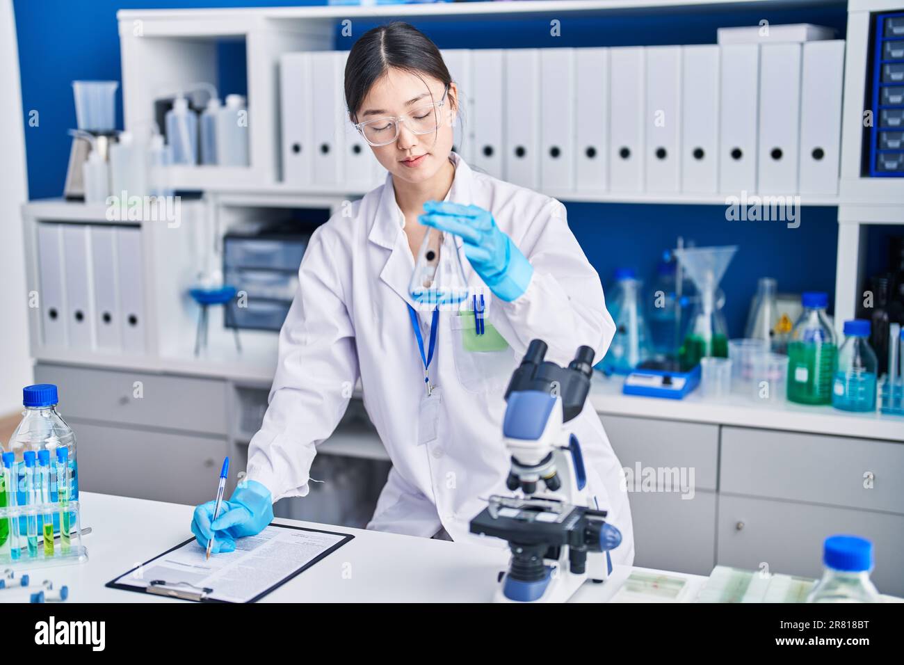 Chinese woman scientist measuring liquid writing on document at ...