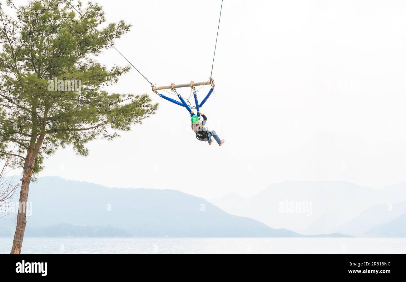 Teenage teen girl bungee flying in rope amusement park. Climbing ...