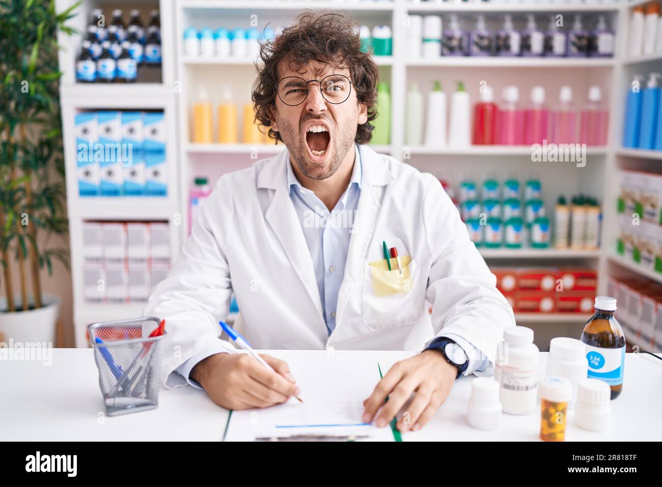 Hispanic young man working at pharmacy drugstore angry and mad ...
