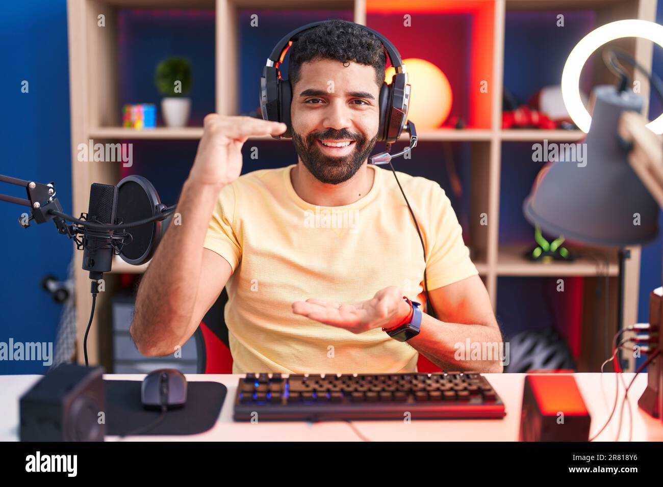 Hispanic man with beard playing video games with headphones gesturing ...