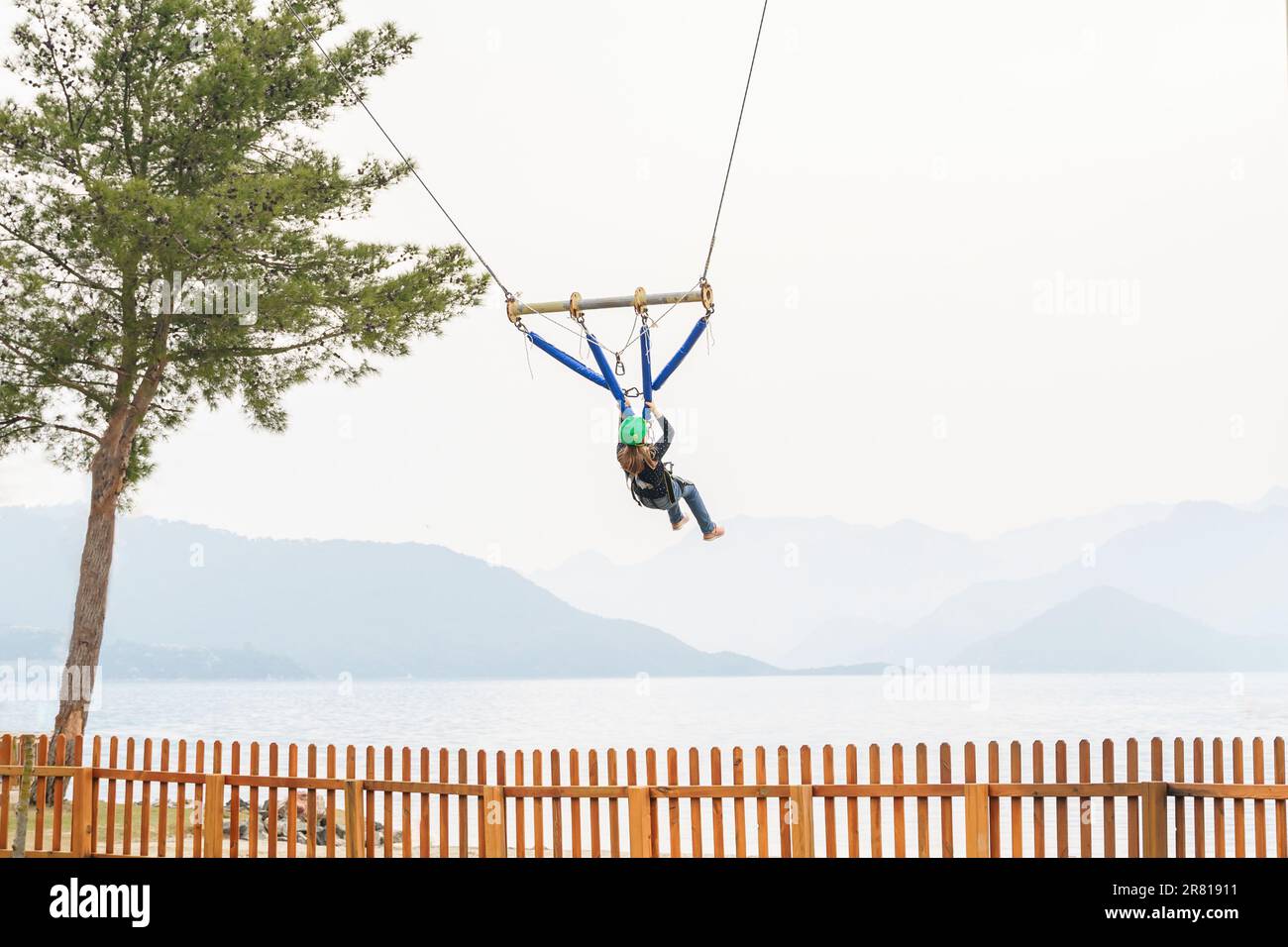 Teenage teen girl bungee flying in rope amusement park. Climbing ...