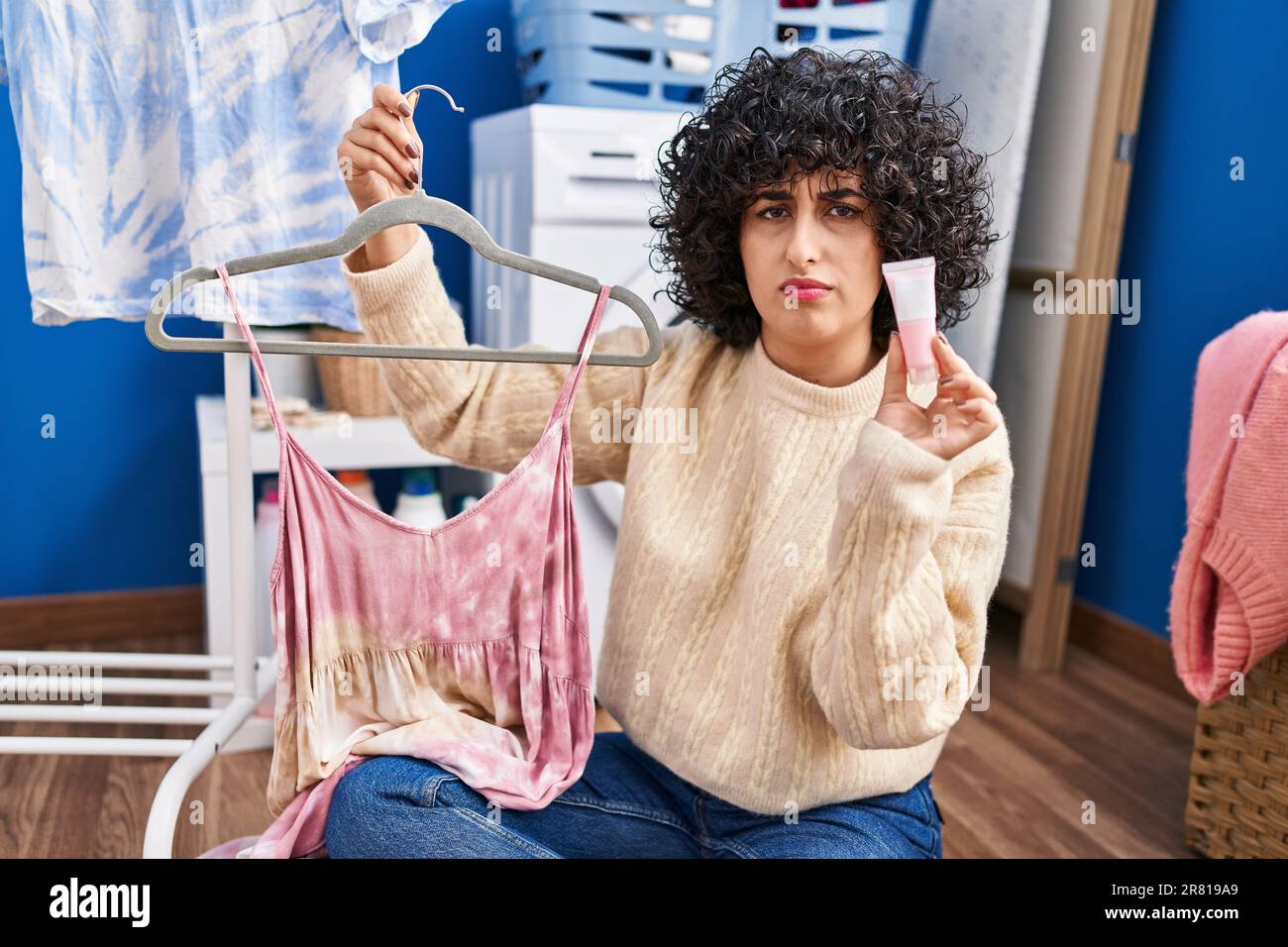 Young brunette woman with curly hair dyeing tye die dress with pink ...