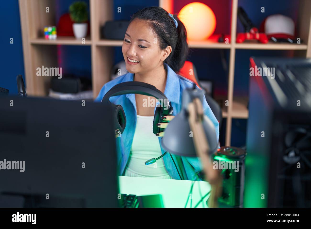 Young chinese woman streamer smiling confident holding headphones at ...