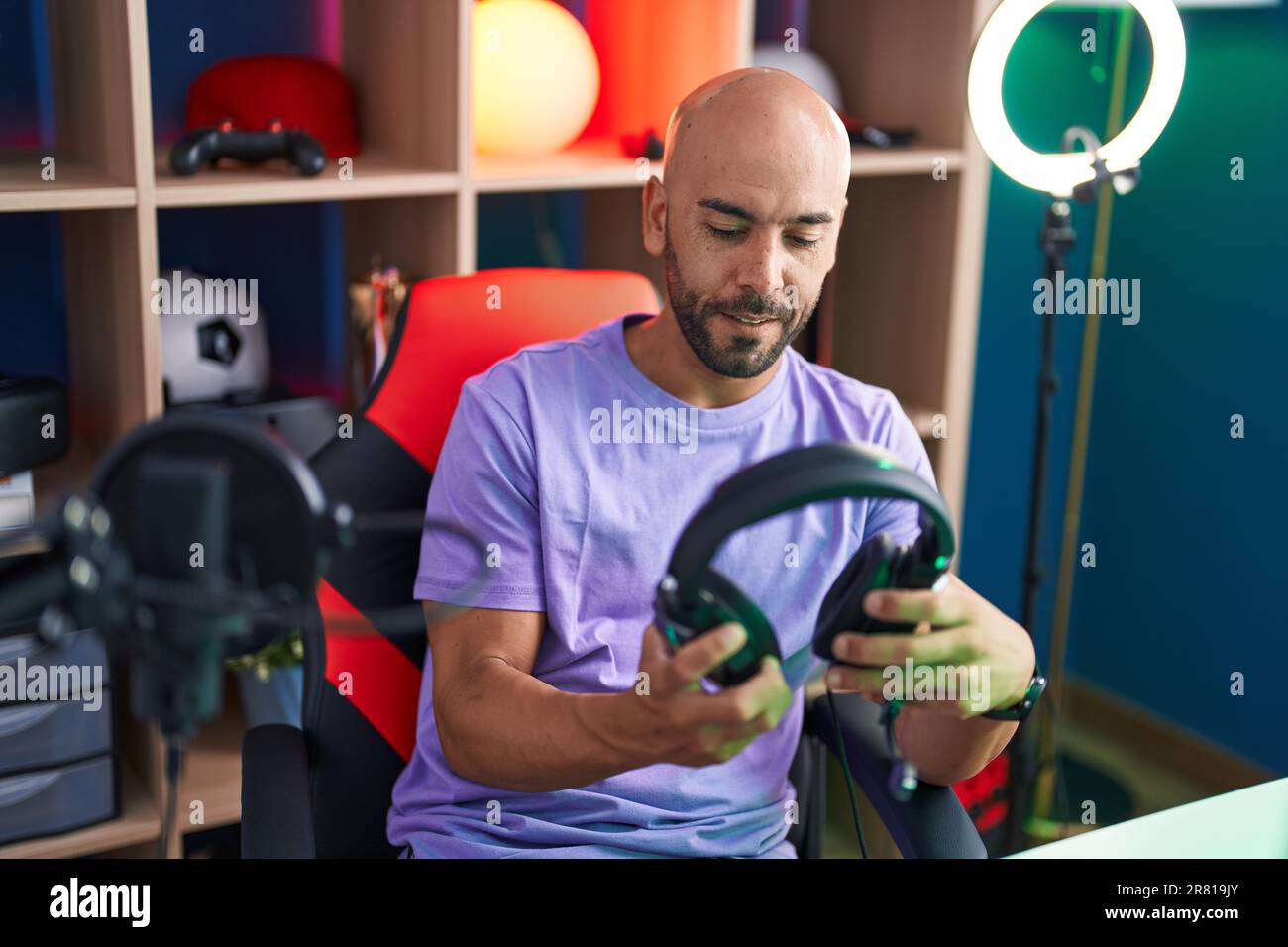 Young bald man streamer smiling confident holding headphones at gaming ...