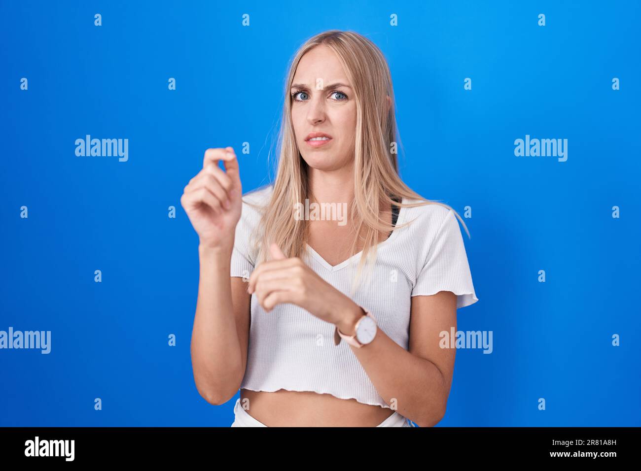 Young caucasian woman standing over blue background disgusted ...
