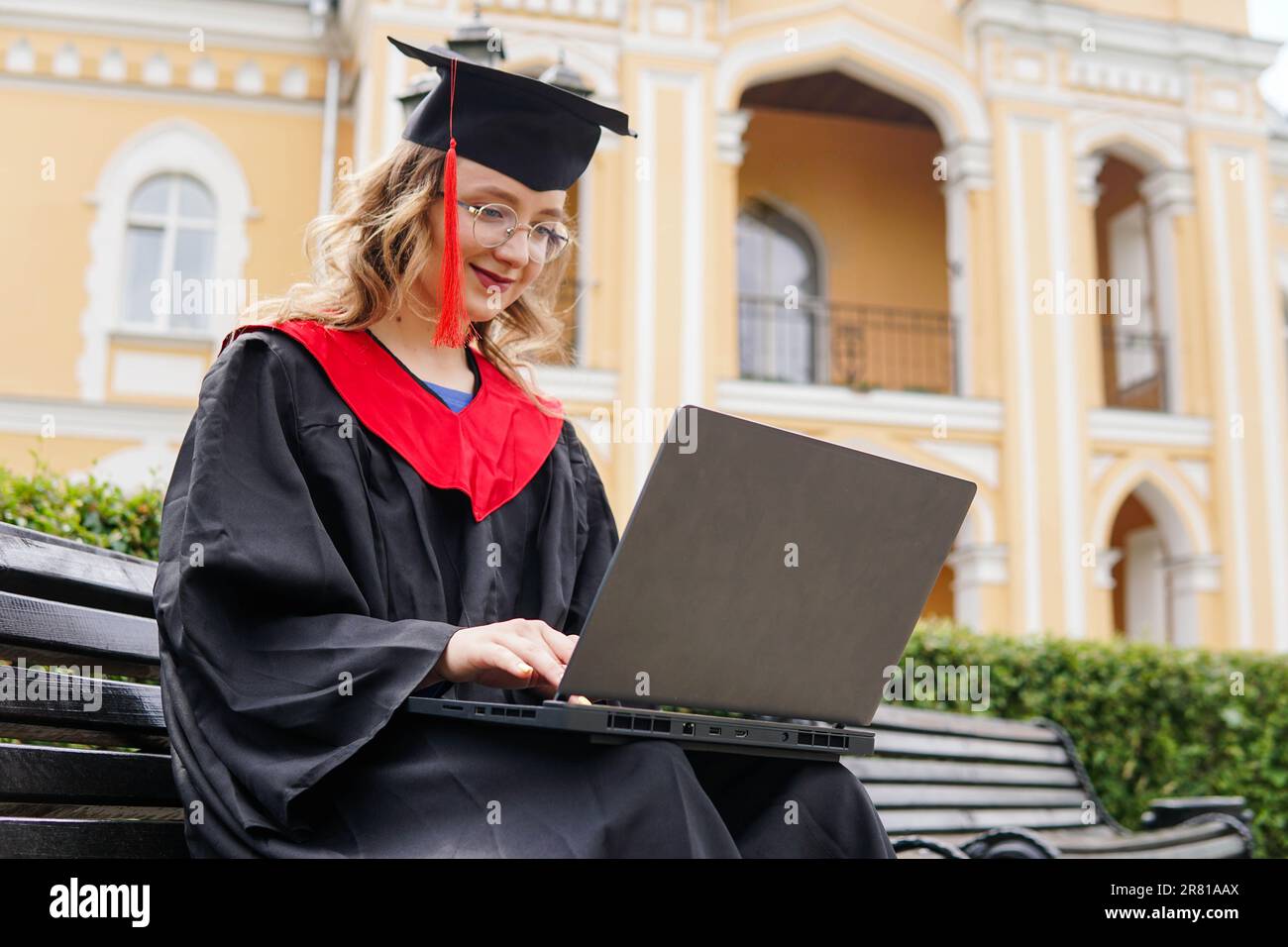 Happy smiling female graduate student in black academic gown with ...