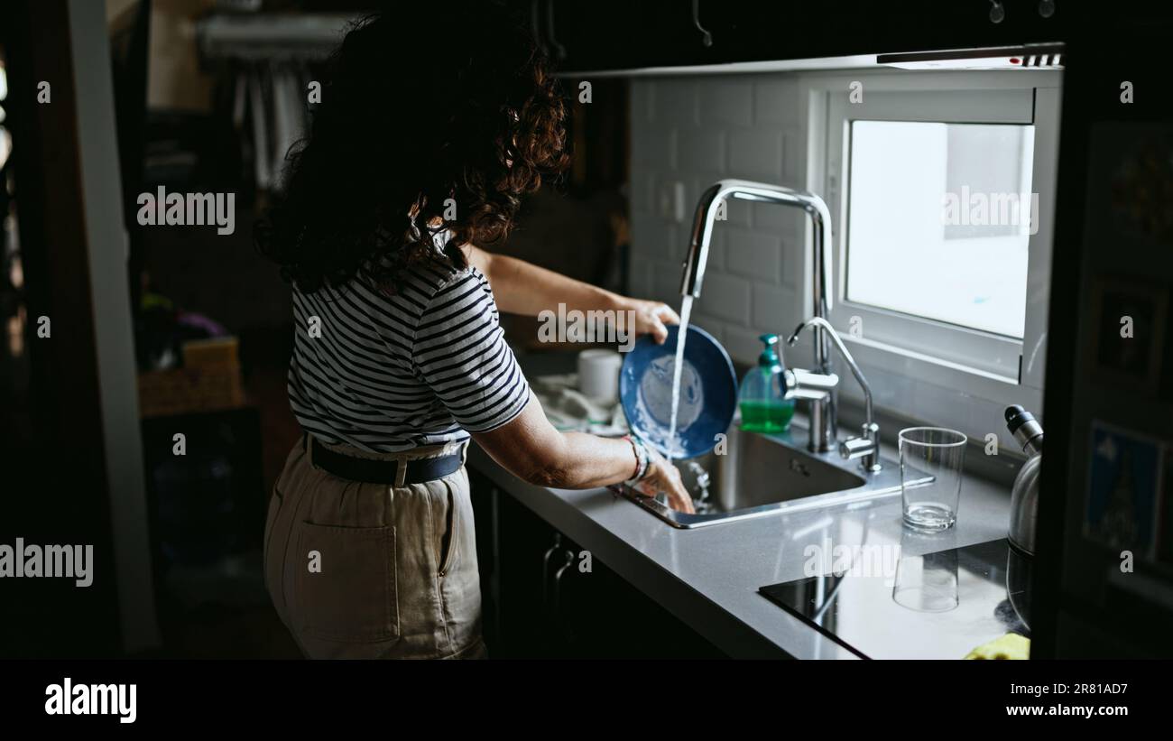 Middle age hispanic woman washing plates at the kitchen Stock Photo - Alamy