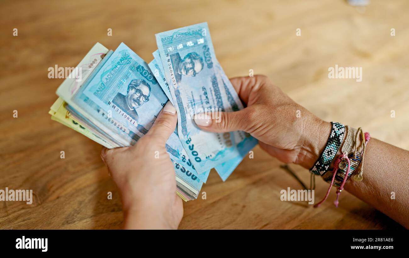 Middle age hispanic woman counting bangladesh taka banknotes at home ...