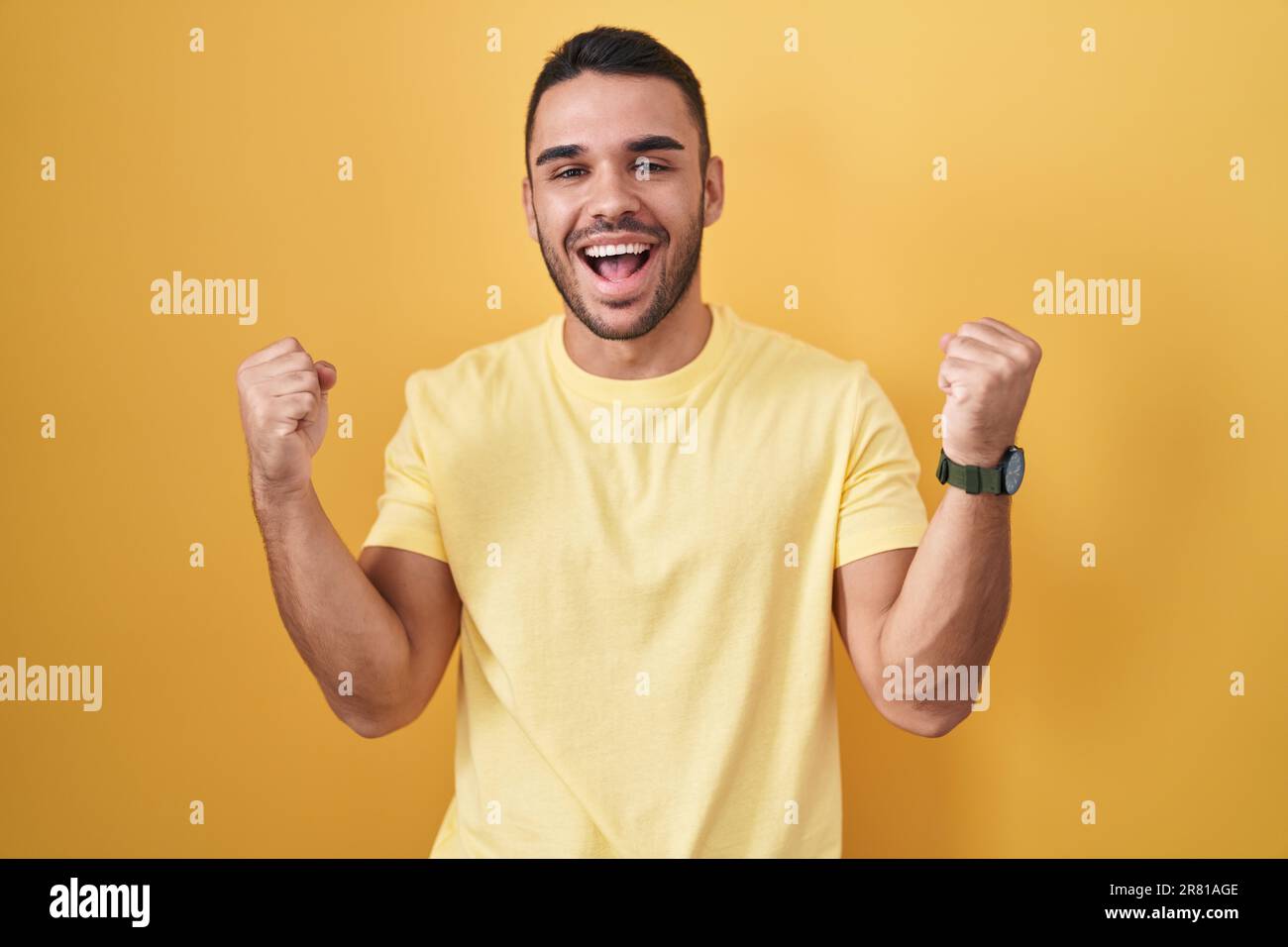 Young hispanic man standing over yellow background celebrating ...