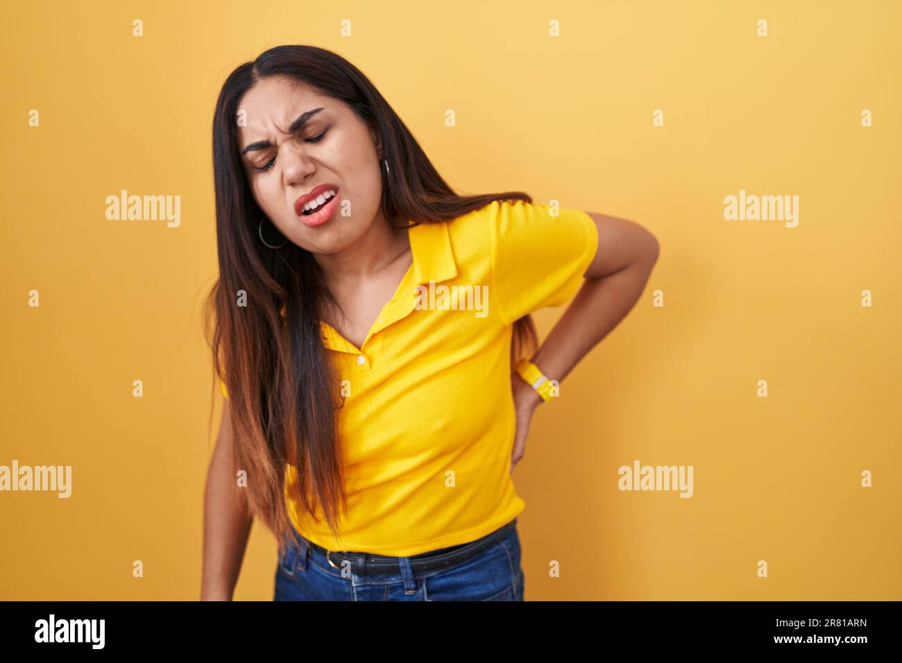 Young arab woman standing over yellow background suffering of backache ...