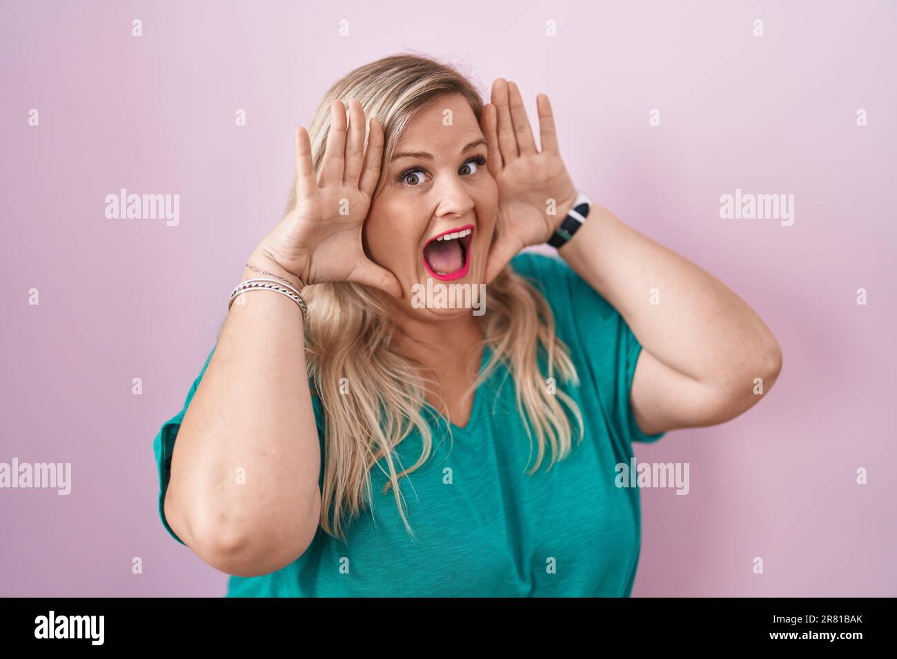 Caucasian plus size woman standing over pink background smiling ...