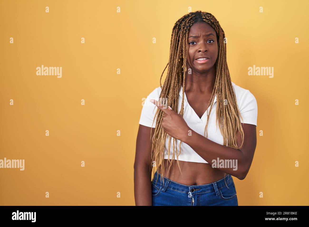 African american woman with braided hair standing over yellow ...