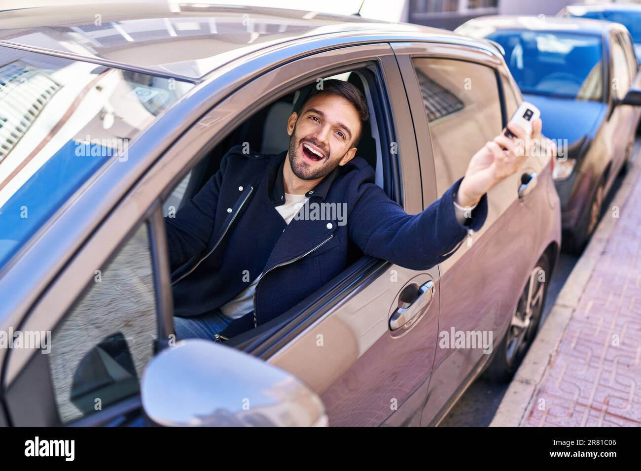Young hispanic man smiling confident holding key of new car at street ...