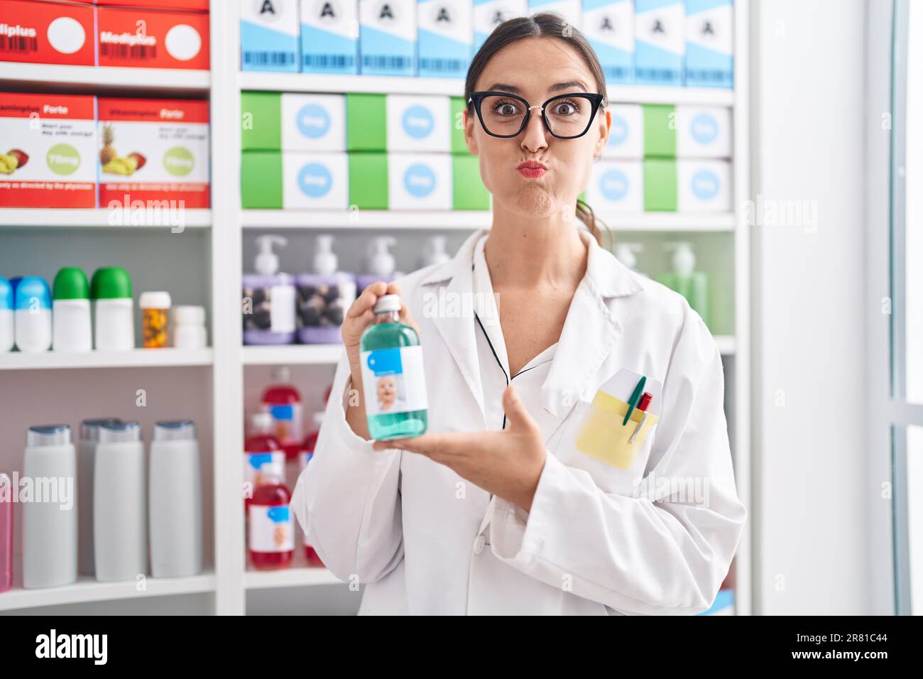 Brunette woman working at pharmacy drugstore holding cough syrup ...