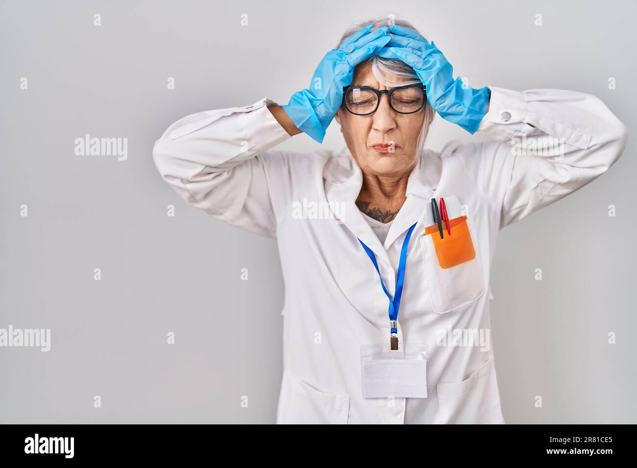 Middle age woman with grey hair wearing scientist robe suffering from ...