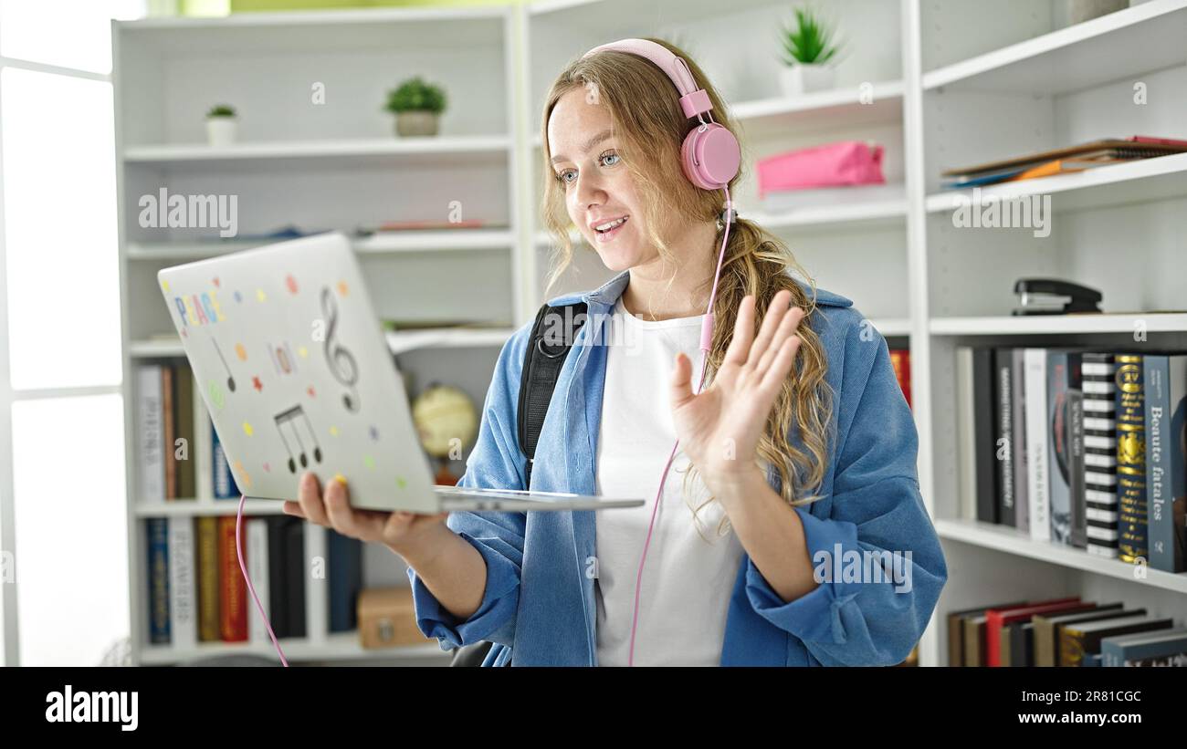 Young blonde woman student having video call standing at library ...
