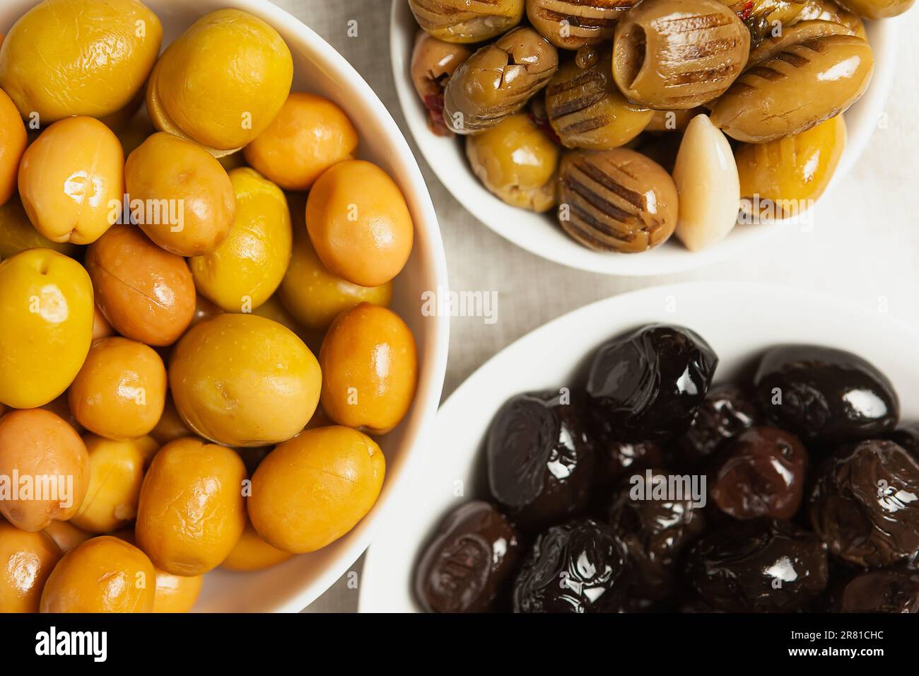 a set of three types of olives in white bowls - whole large green ...