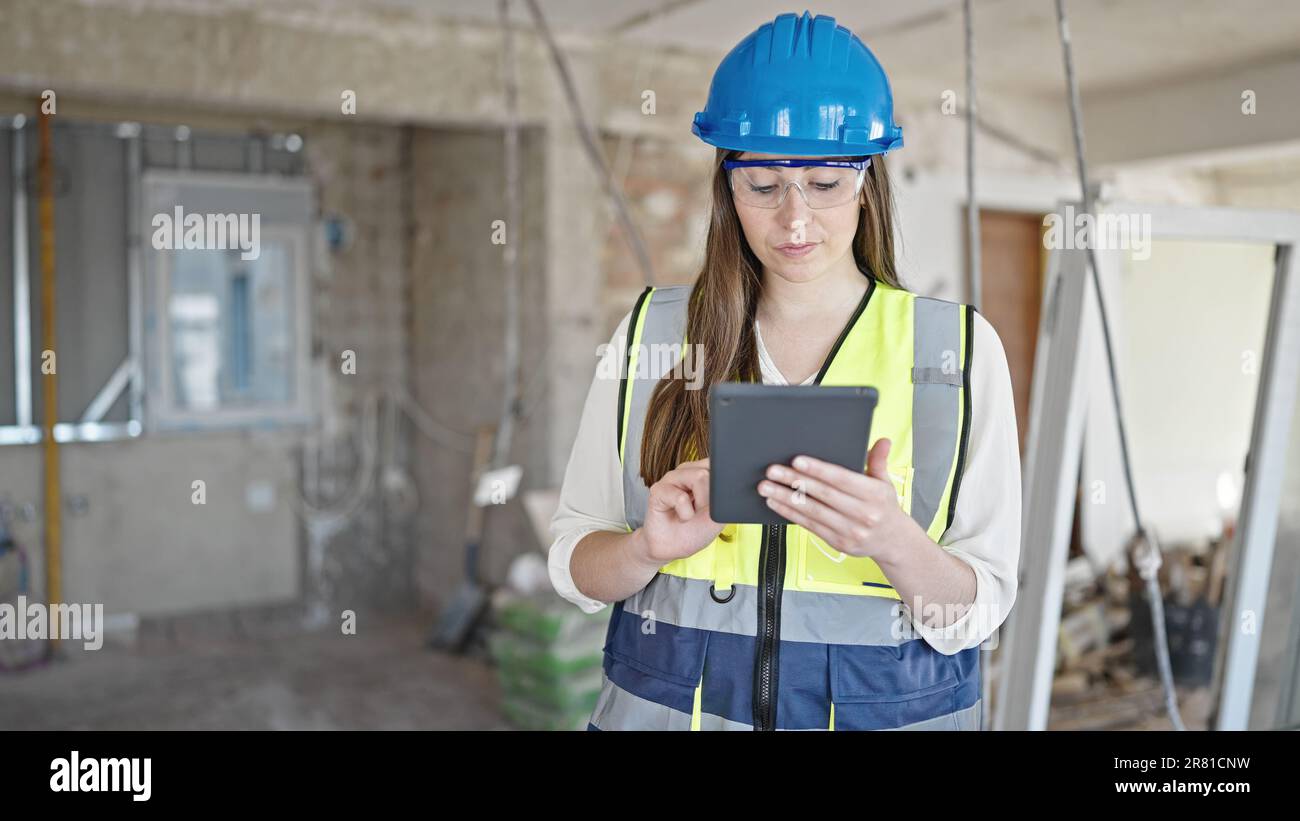 Young beautiful hispanic woman builder using touchpad at construction ...