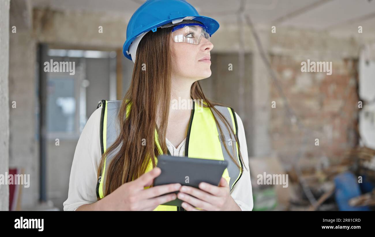 Young beautiful hispanic woman builder using touchpad at construction ...
