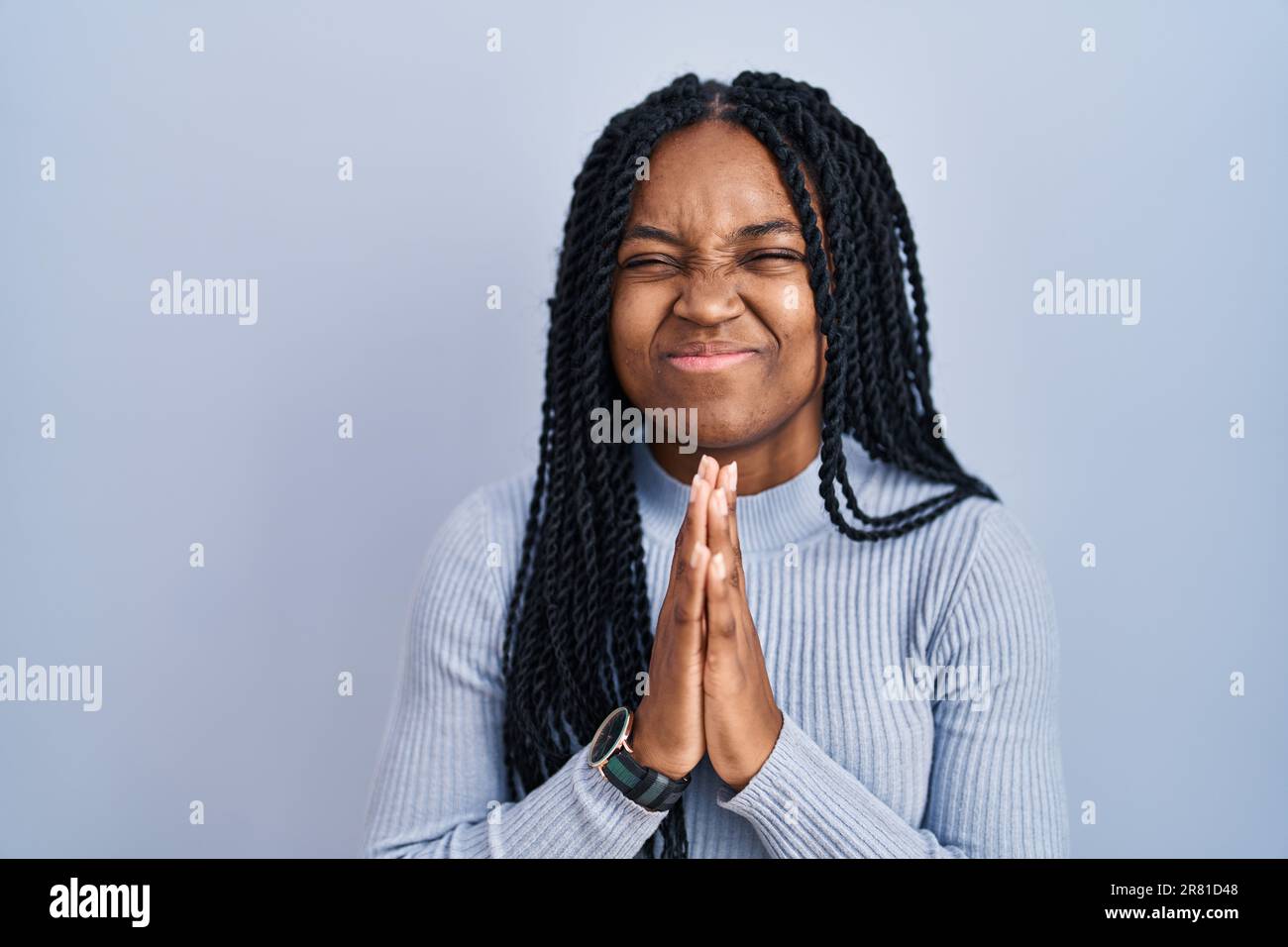 African american woman standing over blue background begging and ...